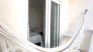 Uma rede em um quarto com uma cama e uma porta de correr de vidro que dá para outro quarto.