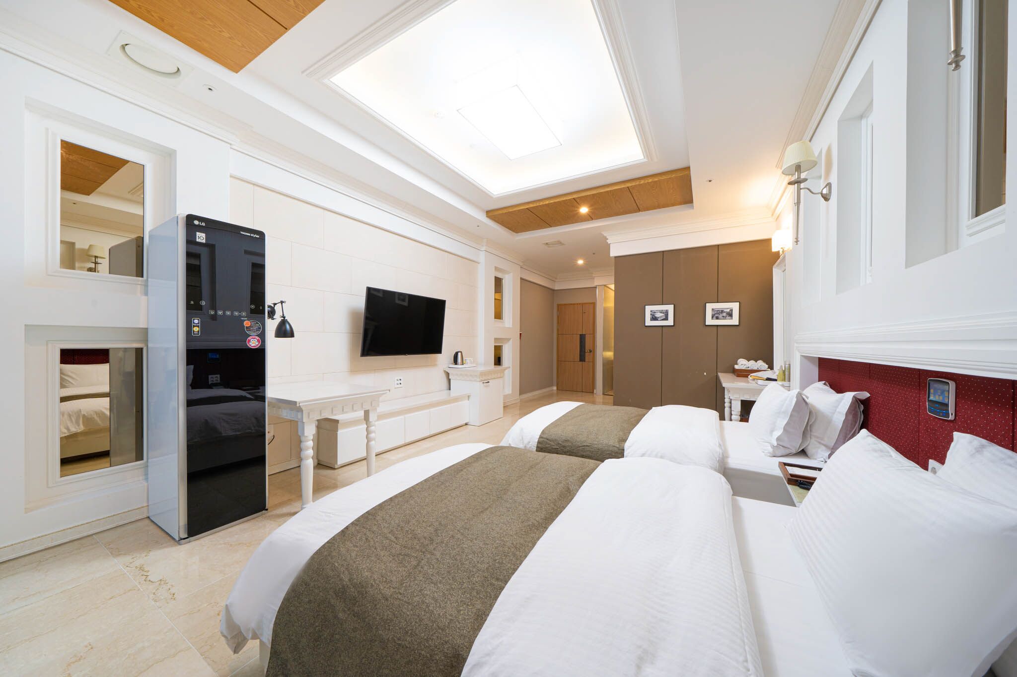 Quarto de hotel com cama, televisão, minibar e claraboia.