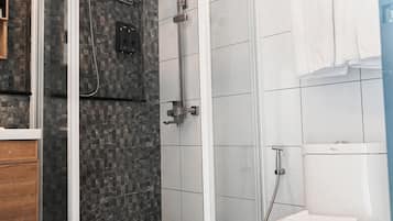 Um banheiro moderno com chuveiro em box de vidro, vaso sanitário branco e toucador de madeira.