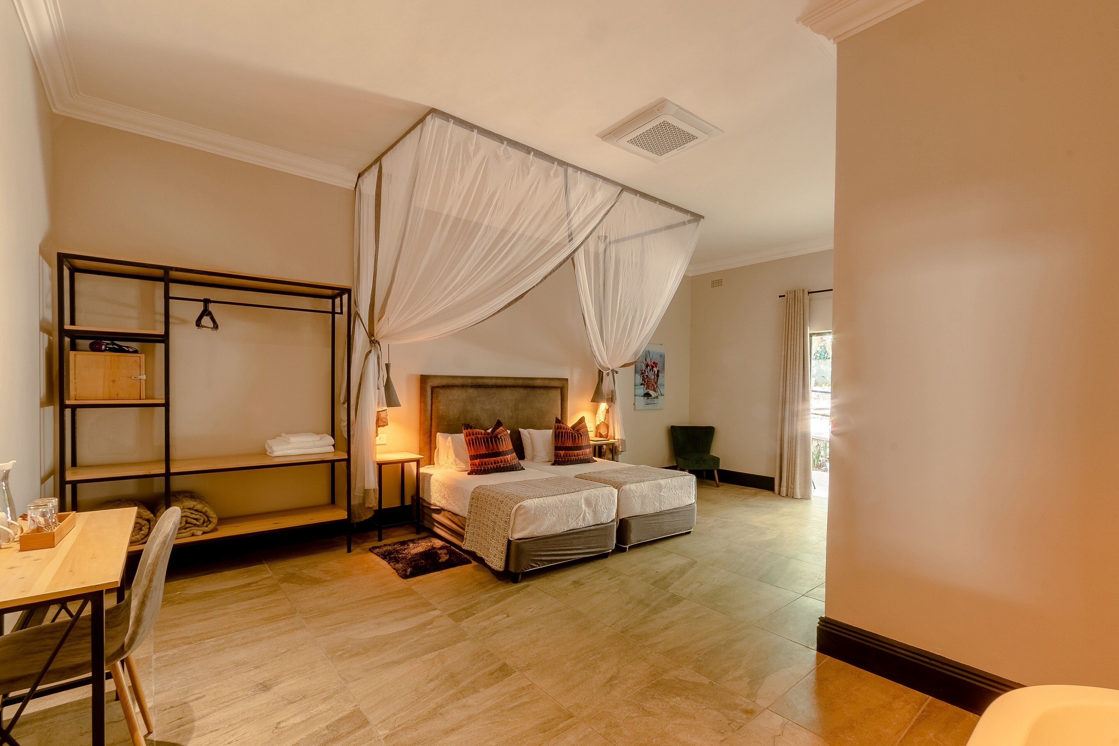 Quarto com uma cama grande, uma mesa de cabeceira, uma cadeira, um guarda-roupa e uma janela com cortinas.