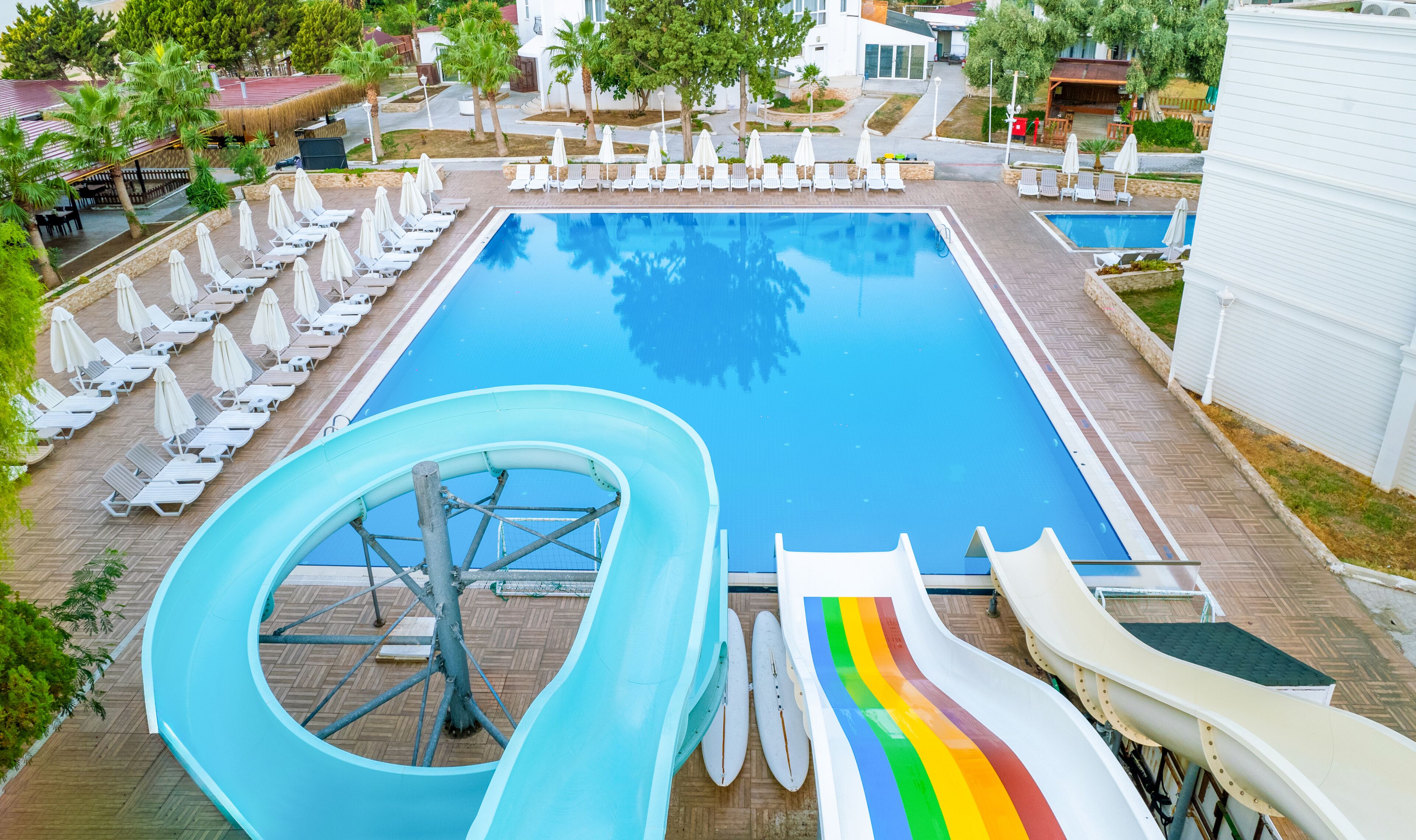 Uma piscina com duas escorregas, espreguiçadeiras e guarda-sóis.