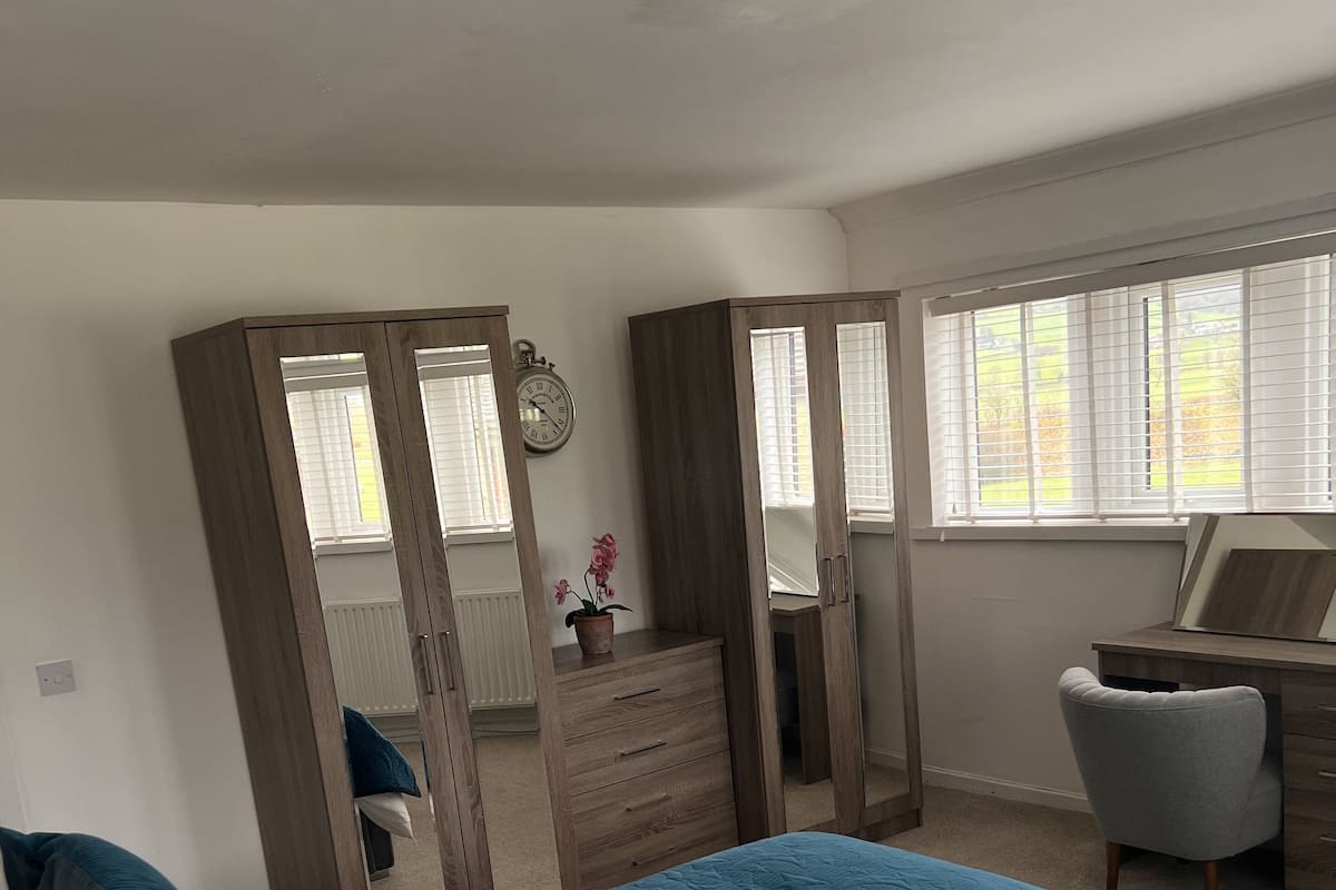Quarto com cama, penteadeira e escrivaninha com cadeira.