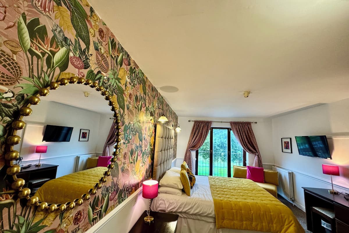 Quarto de hotel com duas camas, um espelho grande, televisão e vista para o exterior.