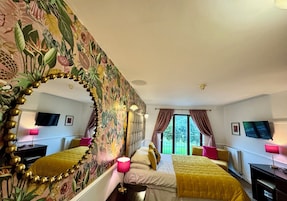Quarto de hotel com duas camas, um espelho grande, televisão e vista para o exterior.