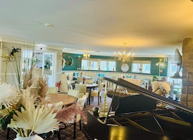 Um piano de cauda em uma sala de estar ampla e elegantemente decorada, com assentos confortáveis e vista para o bar.