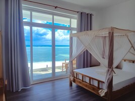 Quarto com cama de madeira, uma janela grande e vista para o mar.