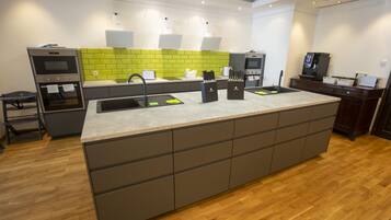 Cozinha moderna com ilha central, forno embutido e painel de parede verde.
