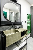 Casa de banho moderna com um espelho grande, uma pia e um porta-toalhas verde.