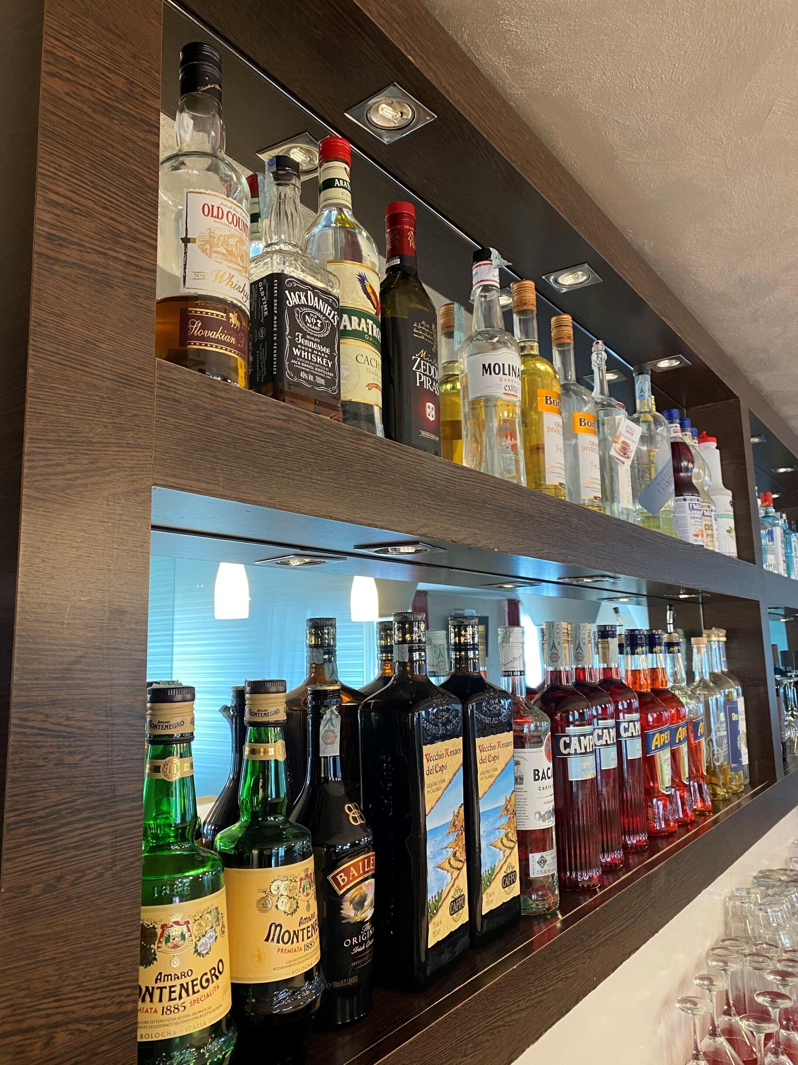 Um bar com diversas garrafas de bebidas, incluindo uísque e vinho.