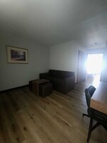 Uma sala de estar com sofá, puf e um quadro na parede.
