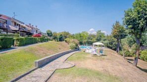 Um bairro residencial com piscina, espreguiçadeiras e um caminho pavimentado.