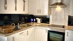 Uma cozinha moderna com armários brancos, uma pia de aço inoxidável, forno embutido e backsplash preto.