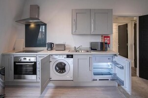 Cozinha compacta com eletrodomésticos embutidos, incluindo fogão, forno, micro-ondas e lava-louças.
