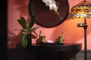 Uma mesa redonda com uma planta em vaso, uma luminária decorativa e uma pequena bandeja com vela e incensos.