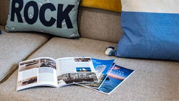 Uma revista aberta em um sofá, com um travesseiro com a inscrição 'ROCK'.