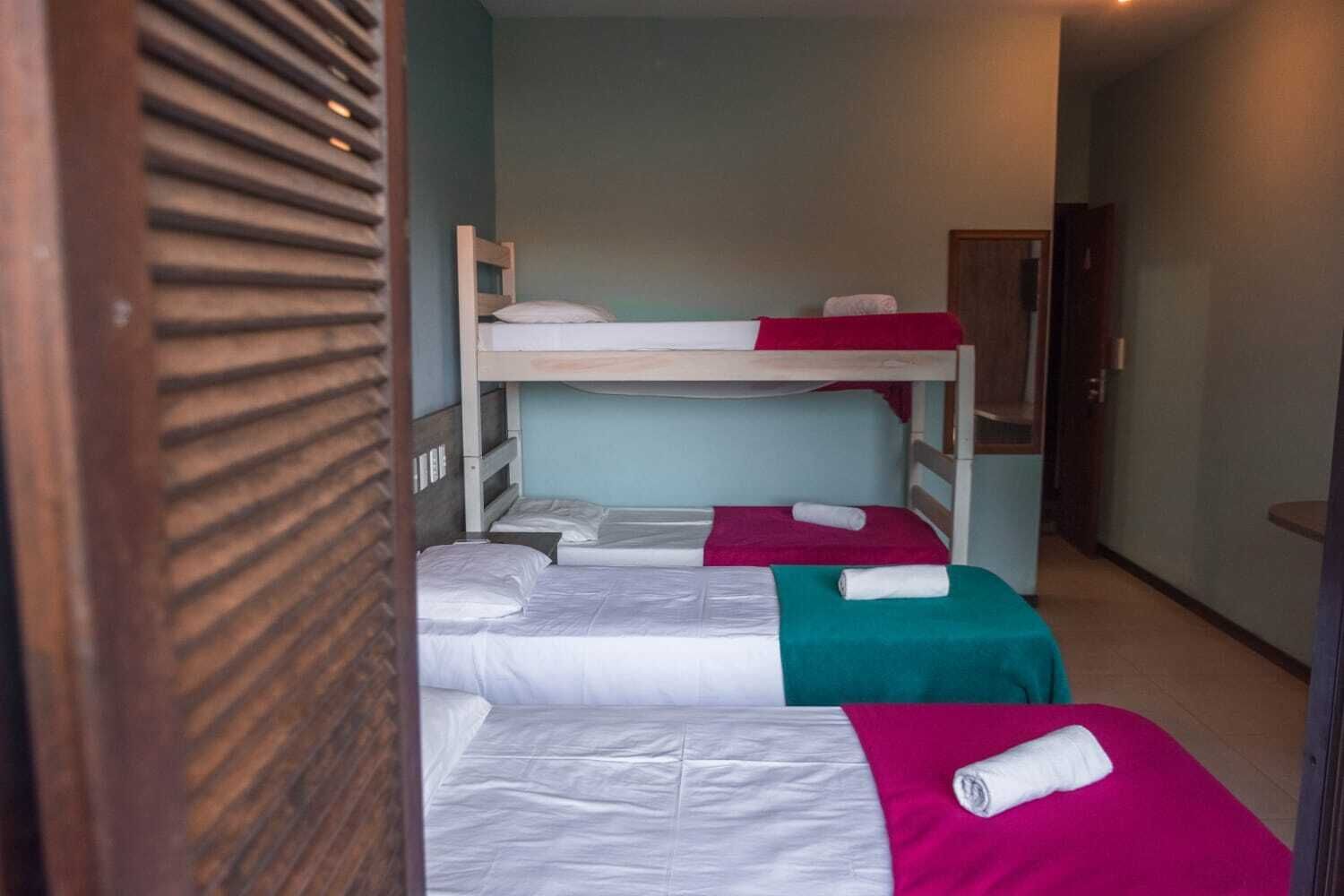 Um quarto de dormitório com beliches, uma porta de madeira e um corredor.