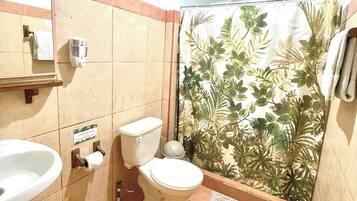 Casa de banho com sanita, lavatório e cortina de chuveiro com padrão floral.