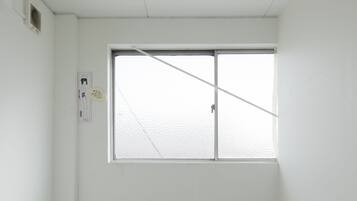 Quarto com uma janela grande, um abajur e um radiador.