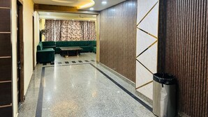 Um hall de hotel com teto curvo, balcão de recepção, sofá verde e uma lixeira.