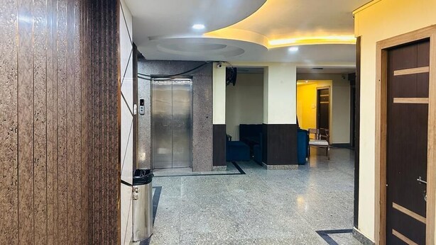Um hall de hotel com design moderno, apresentando teto curvo, balcão de recepção e área de estar.