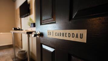 Uma porta com uma placa que diz '10 | CARNEDDAU' e uma televisão presa na parede acima.