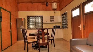 Uma cozinha compacta com mesa e cadeiras, geladeira e aquecedor de água.
