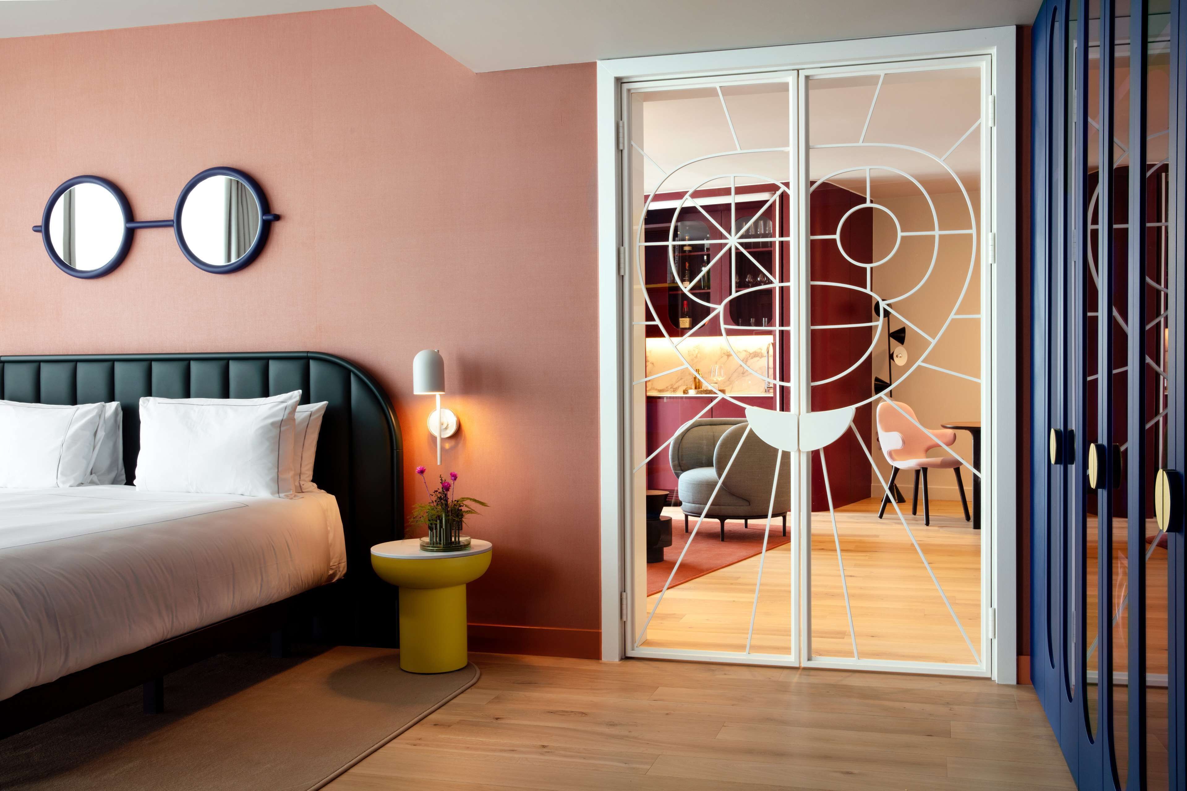 Quarto com cama, mesa de cabeceira e espelho fixado na parede.