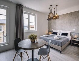 Quarto moderno com cama, mesa de cabeceira e uma mesa redonda com cadeiras.