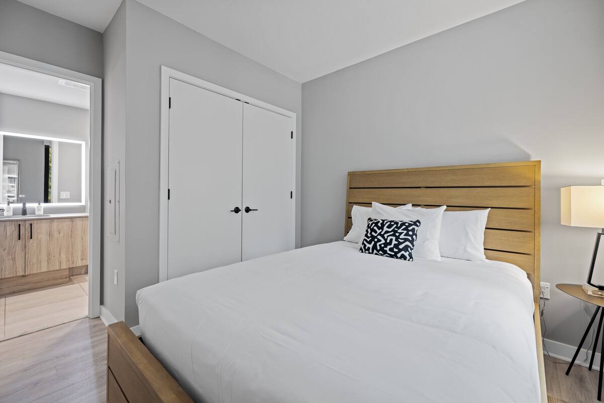 Quarto moderno com uma cama grande, cabeceira de madeira e mesa de cabeceira.