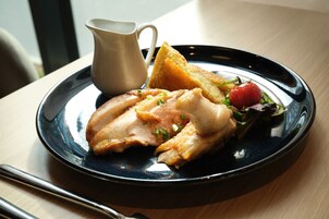 Um prato com comida, uma chávena e um garfo sobre uma mesa.