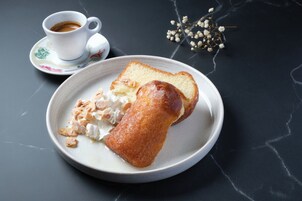 Um prato com um pastel e uma xícara de café sobre uma superfície escura.