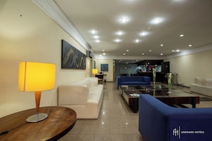 Um saguão de hotel moderno com um sofá, uma mesa de centro e um abajur.