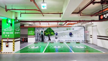 Uma estação de carregamento para veículos elétricos com um sinal verde, um mural de árvore e uma parede com instruções.