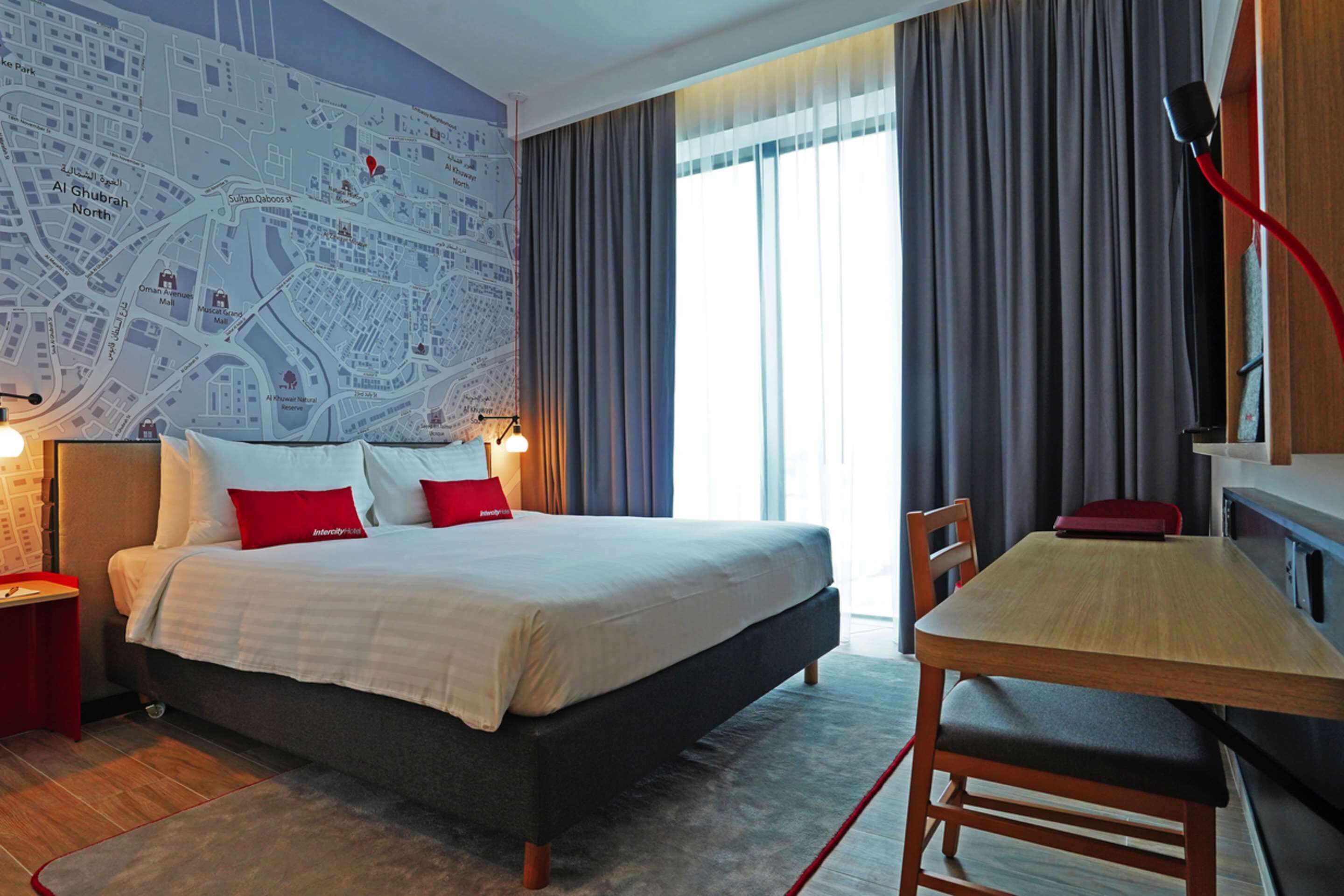 Quarto de hotel com uma cama grande, uma mesa de madeira e um mapa na parede.