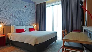 Quarto de hotel com uma cama grande, uma mesa de madeira e um mapa na parede.