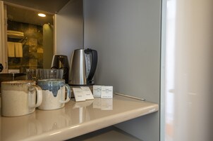 Uma bancada de cozinha com uma cafeteira, duas canecas e algumas cartas.