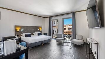 Quarto de hotel moderno com cama, escrivaninha, computador, cadeira e televisão.