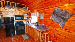 Uma cozinha em estilo cabana de tronco, com paredes de madeira, um troféu de pele pendurado e eletrodomésticos modernos.