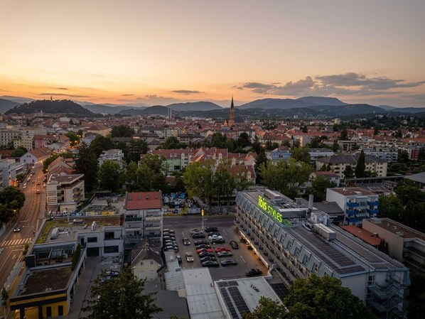 Vista urbana com um edifício em destaque identificado como 'ibis styles', apresentando um design moderno com painéis solares.