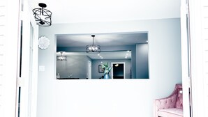 Uma sala de estar moderna com um espelho grande, um sofá rosa e um vaso decorativo.