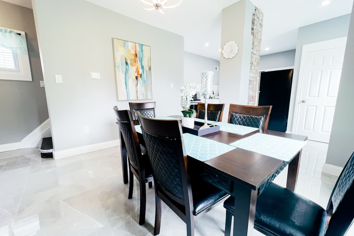 Uma sala de jantar com uma mesa retangular, seis cadeiras e um candelabro.