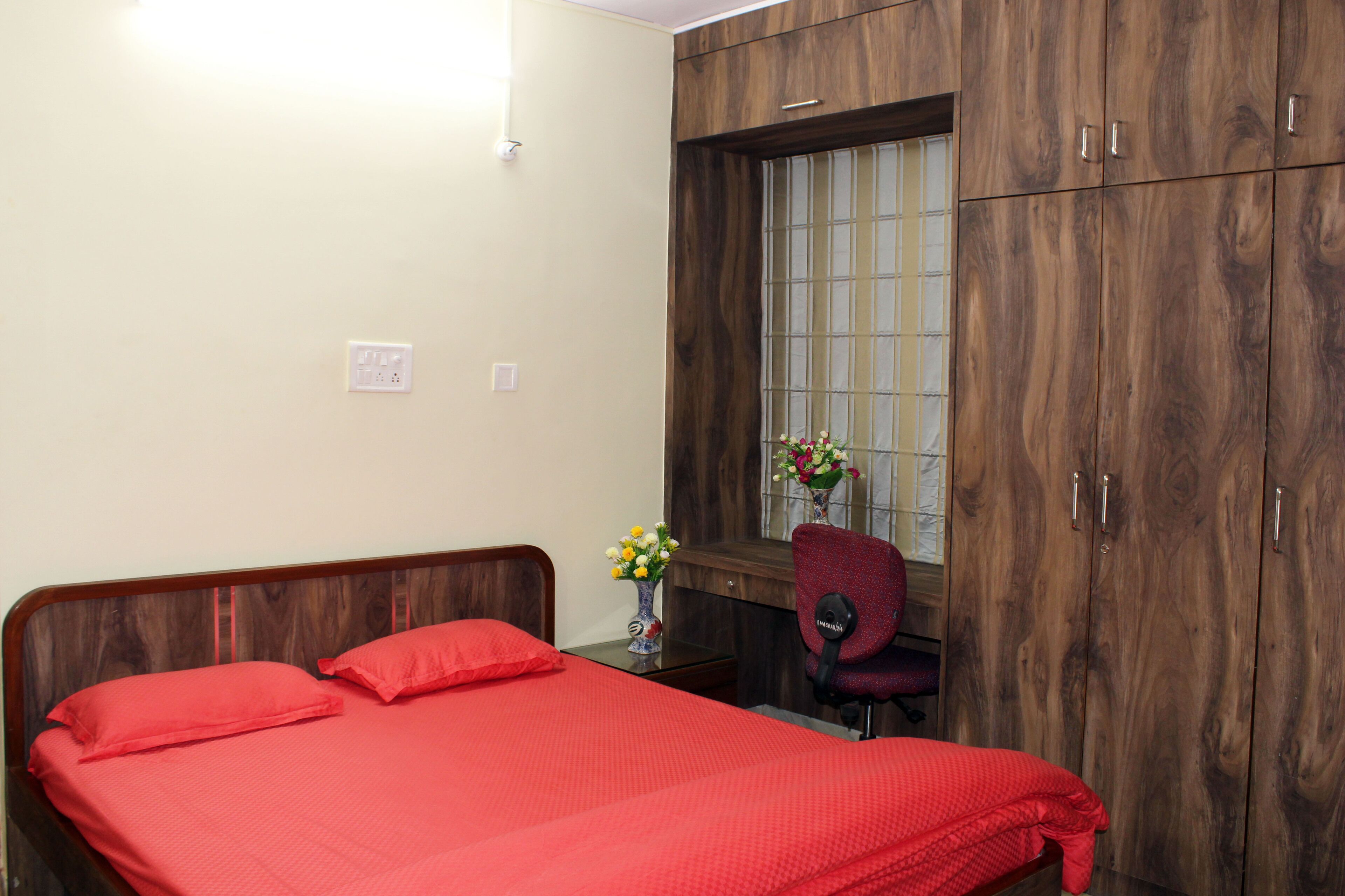Um quarto com uma cama de madeira, uma escrivaninha com cadeira e um guarda-roupa.