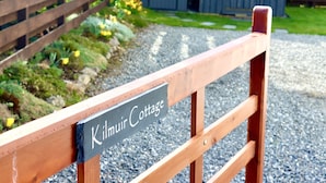 Um portão de madeira com uma placa que diz 'Kilmuir Cottage'.
