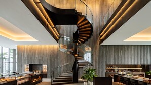 Um interior moderno com escada em espiral, área de cozinha e espaço para refeições.