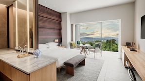 Quarto de hotel moderno com uma cama grande, uma escrivaninha e varanda com vista para a cidade.
