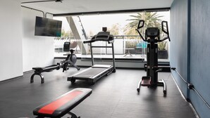 Academia moderna com esteira, banco e aparelho de musculação.