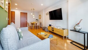 Uma sala de estar moderna com sofá, mesa de centro, TV e um espaço de jantar com cadeiras e mesa.