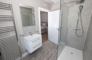 Casa de banho moderna com cabine de duche em vidro, toucador branco e duche amplo.