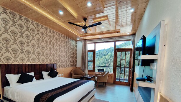 Quarto com uma cama grande, ventilador de teto, TV fixada na parede e vista para o exterior.