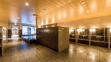 Banheiro público com bancadas de granito, piso ladrilhado e teto de madeira.